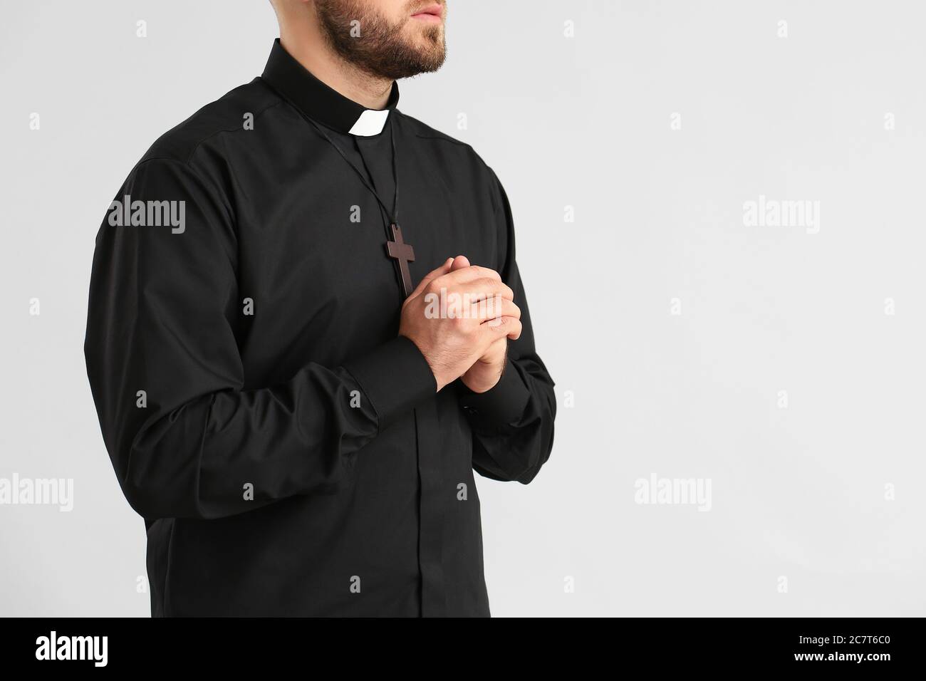 Young priest praying to God on light background Stock Photo - Alamy