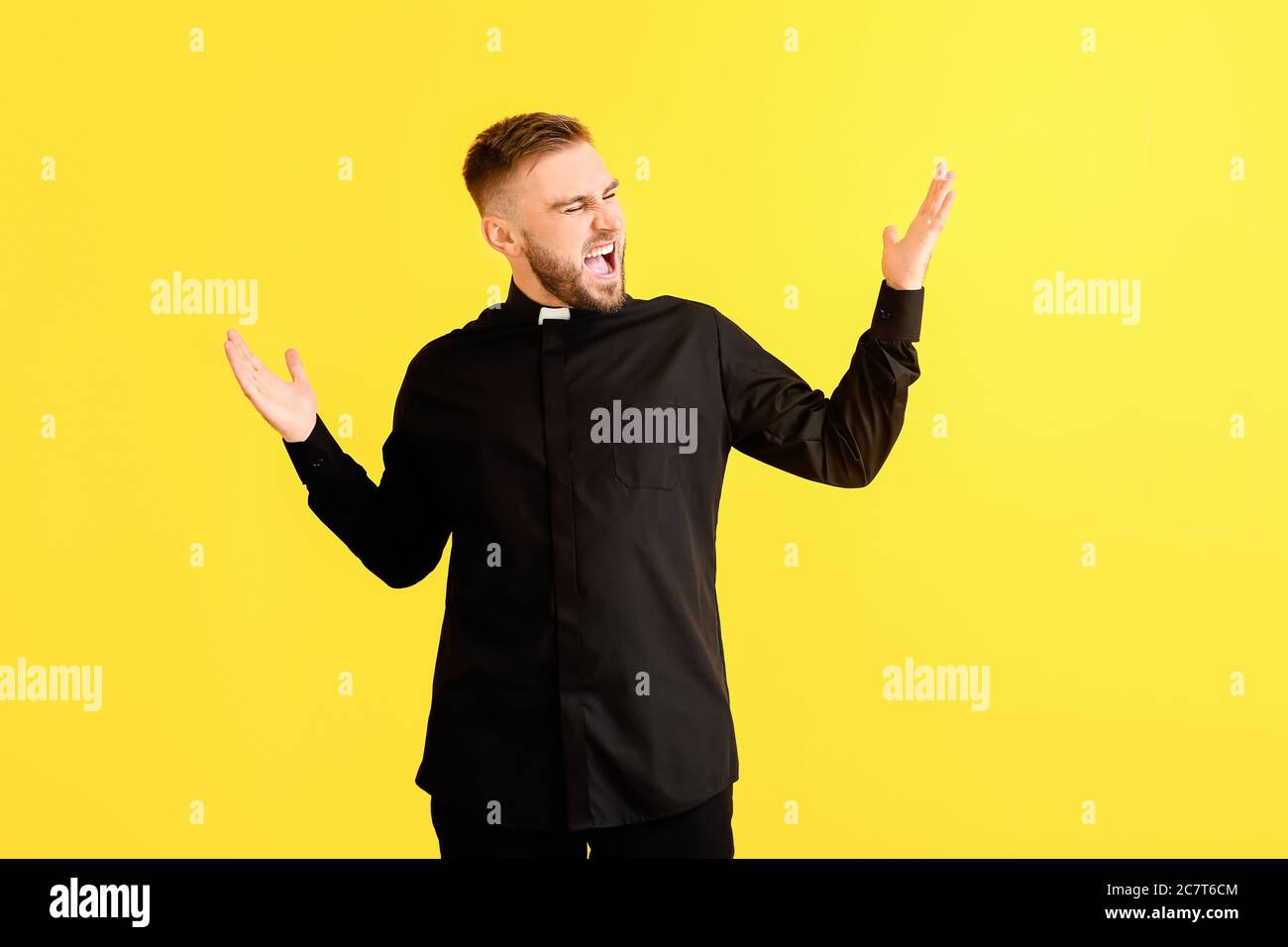 Angry young priest on color background Stock Photo - Alamy