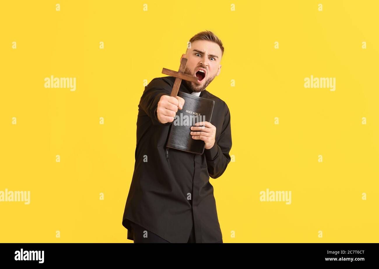 Scared young priest with Bible and cross on color background Stock ...