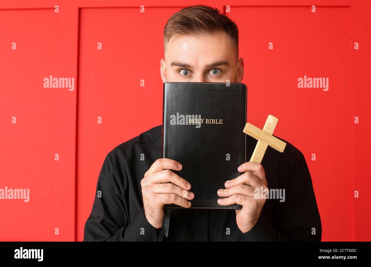 Young priest with Bible on color background Stock Photo - Alamy