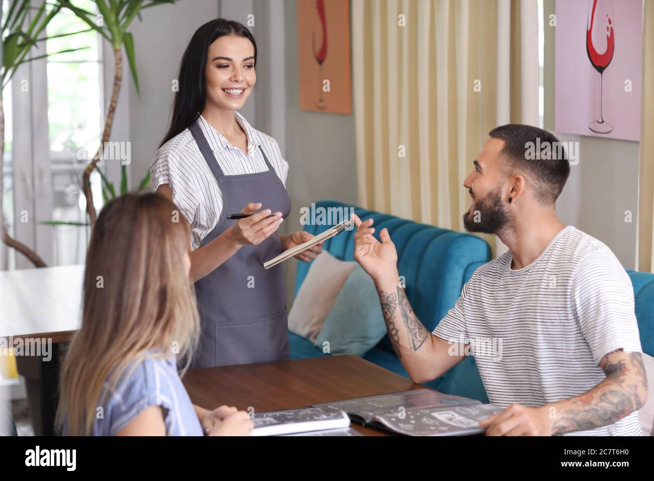 Waitress serving clients in restaurant Stock Photo - Alamy