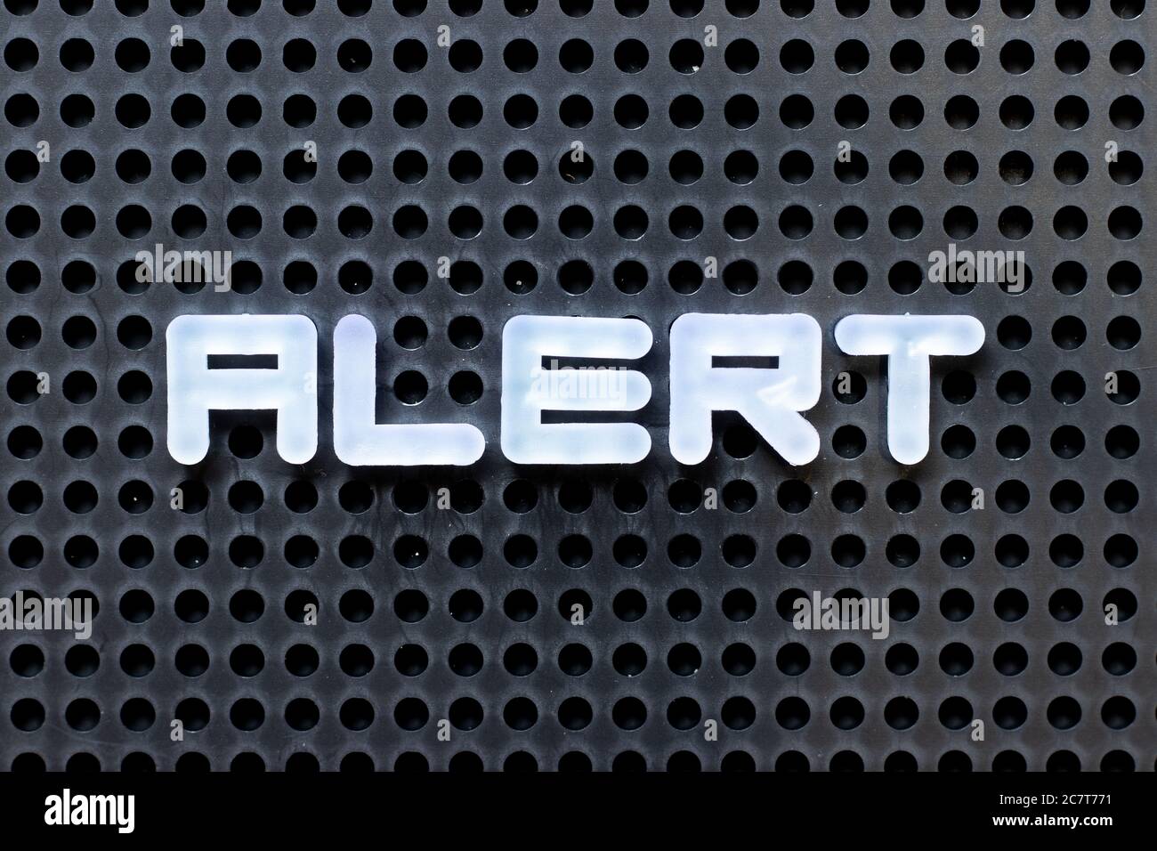 White color alphabet with word alert on black pegboard background Stock ...