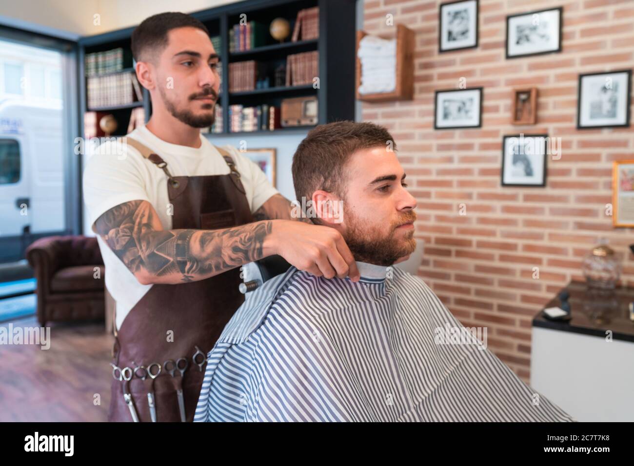 Closeup of a hairdresser with tattoos putting a neck strip around the ...