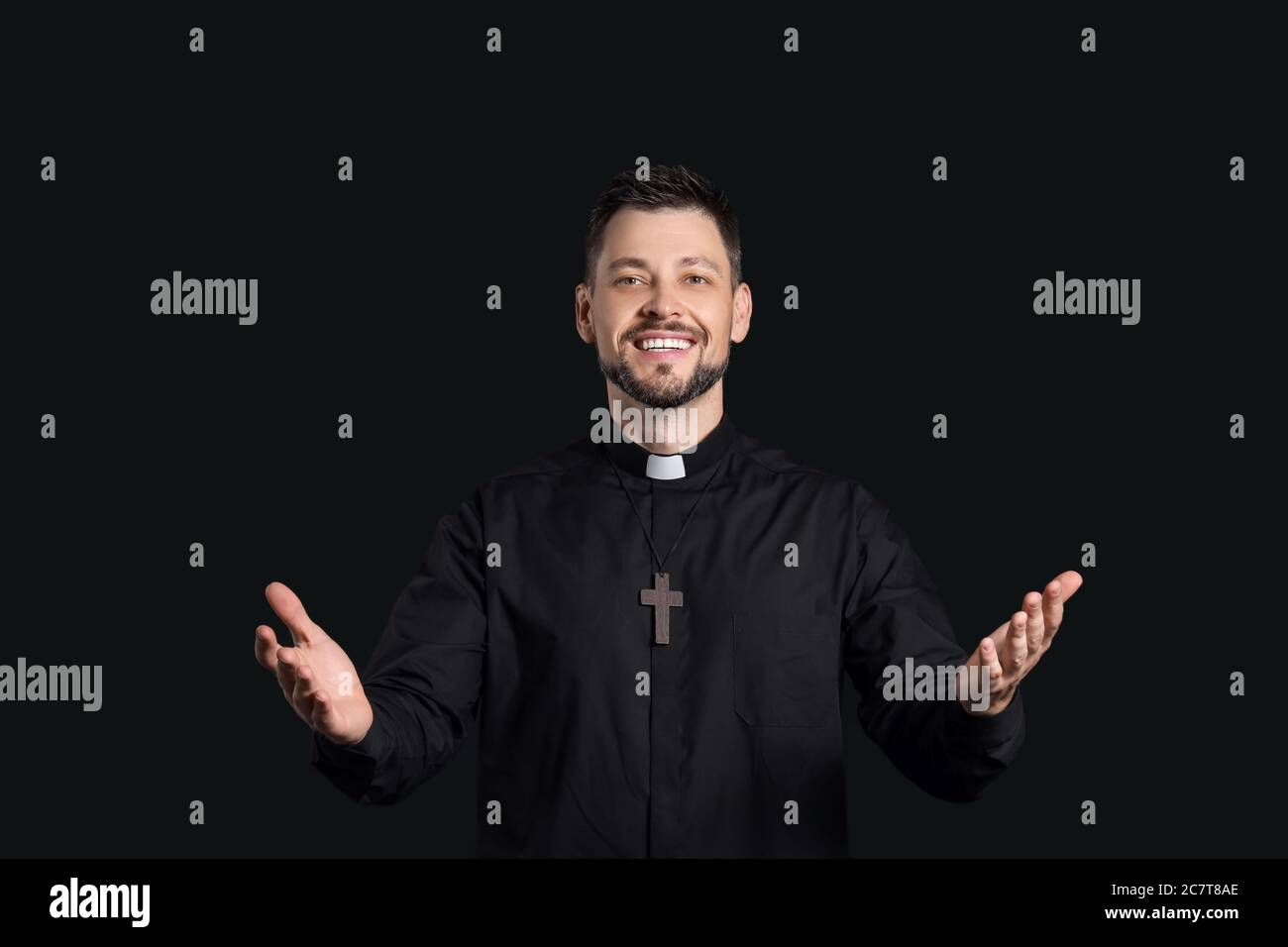 Handsome priest on dark background Stock Photo - Alamy