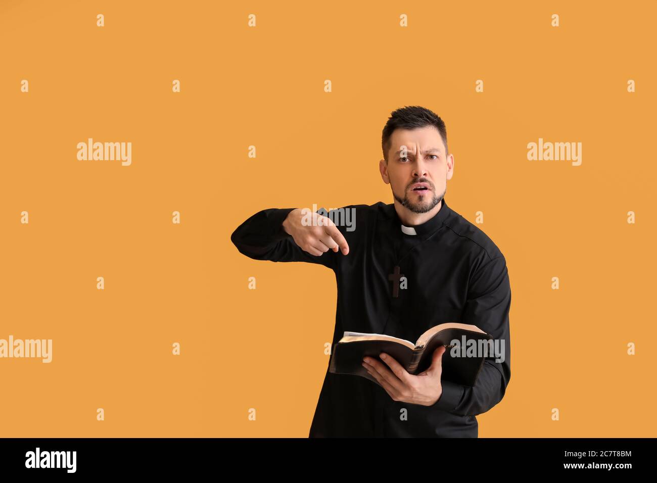 Angry priest with Bible on color background Stock Photo - Alamy