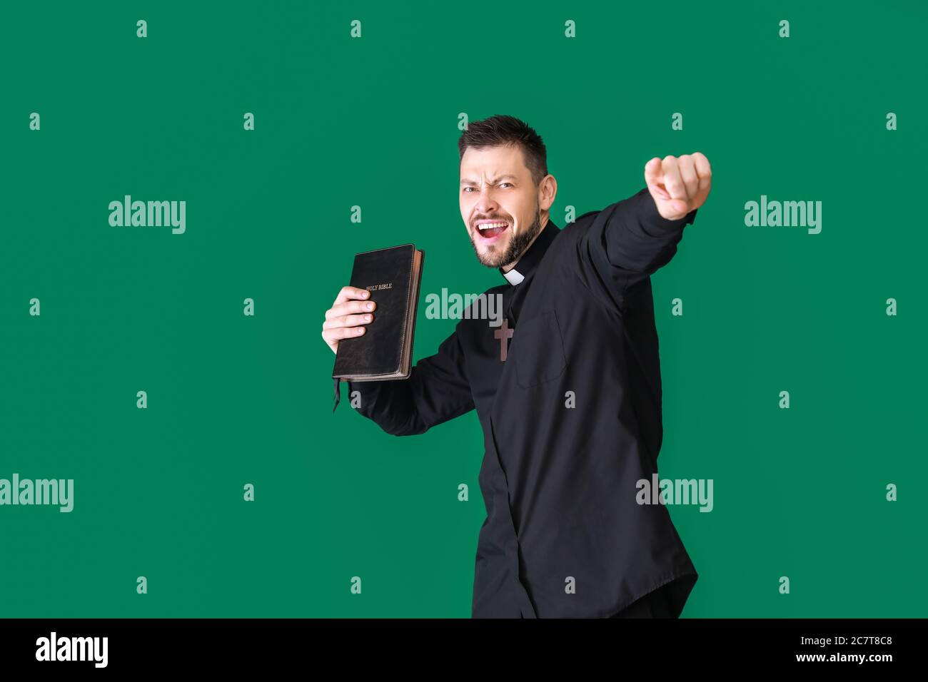 Angry priest with Bible on color background Stock Photo - Alamy