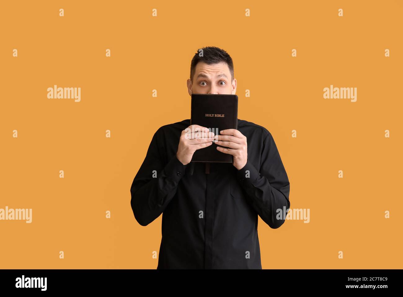 Shocked priest with Bible on color background Stock Photo - Alamy