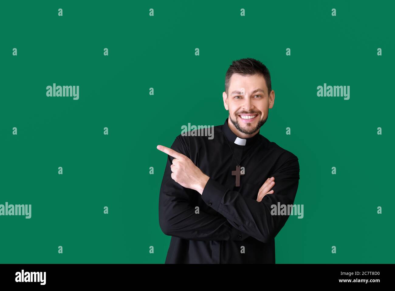 Handsome priest pointing at something on color background Stock Photo ...