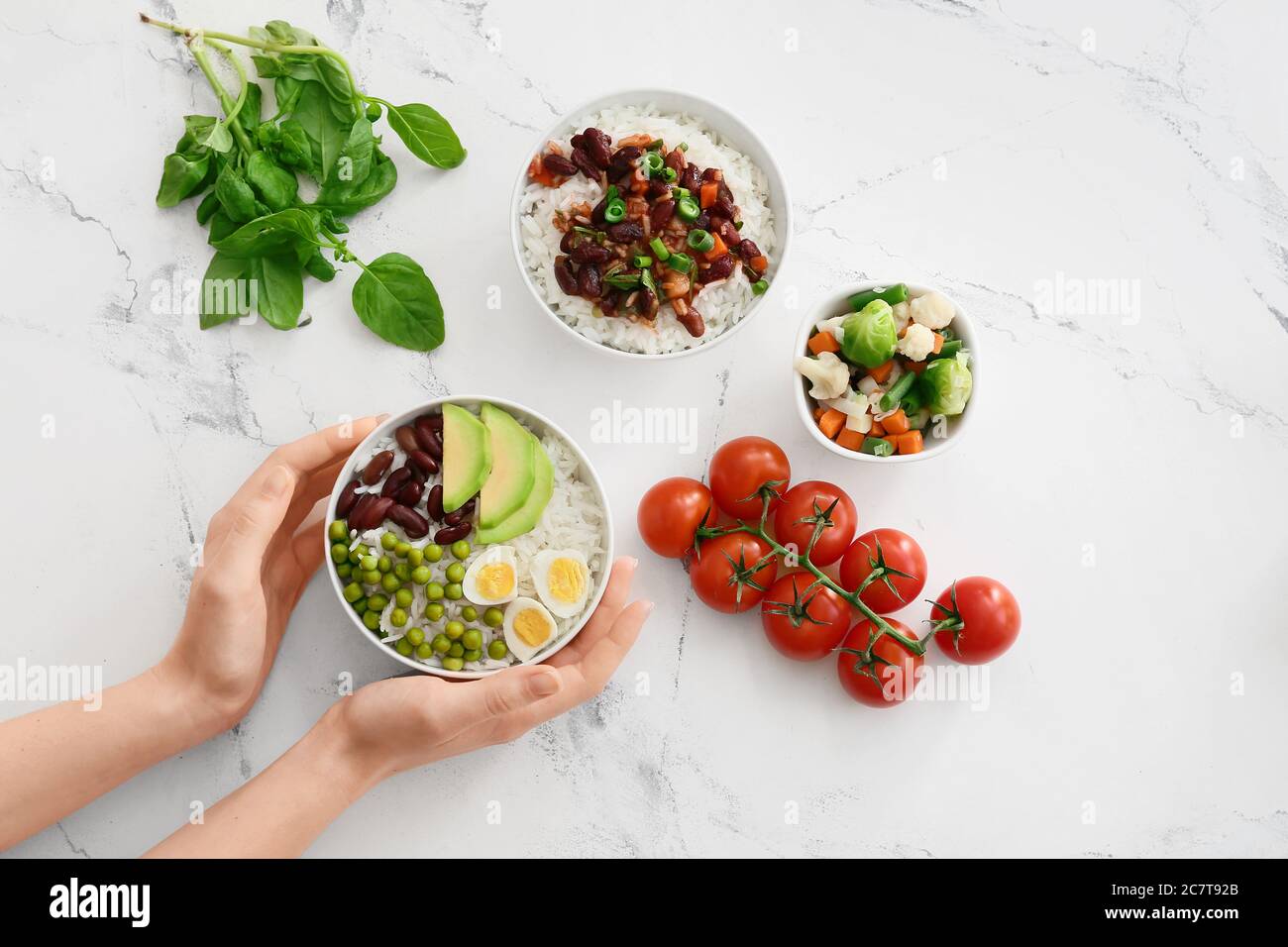 Female hands with tasty rice and beans in bowl and vegetables on white ...