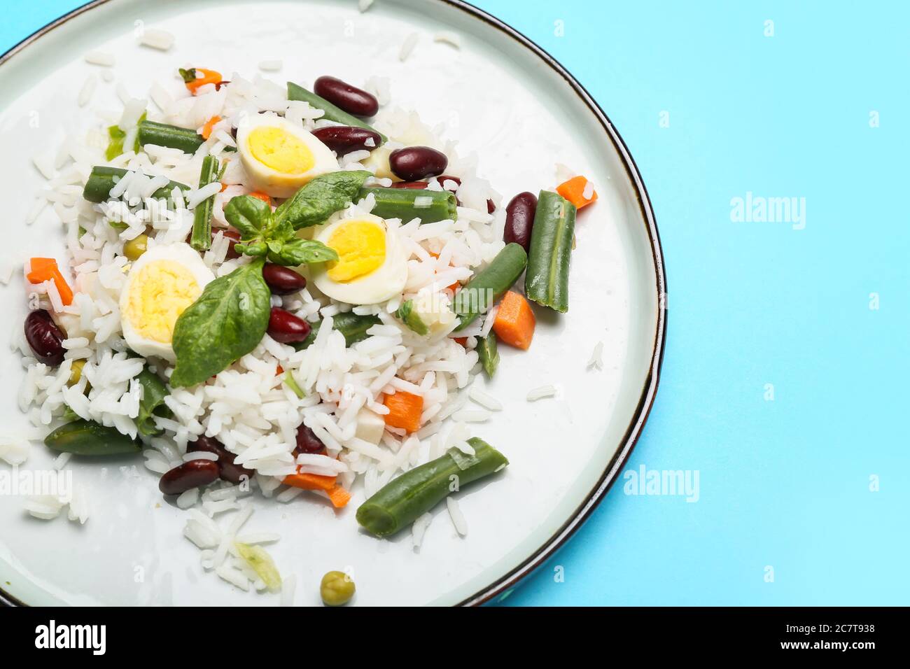 Plate with tasty rice, beans, egg and vegetables on color background ...