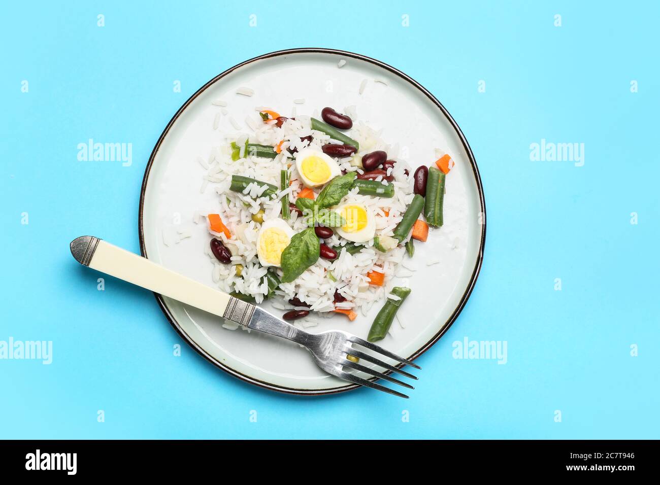 Plate with tasty rice, beans, egg and vegetables on color background ...