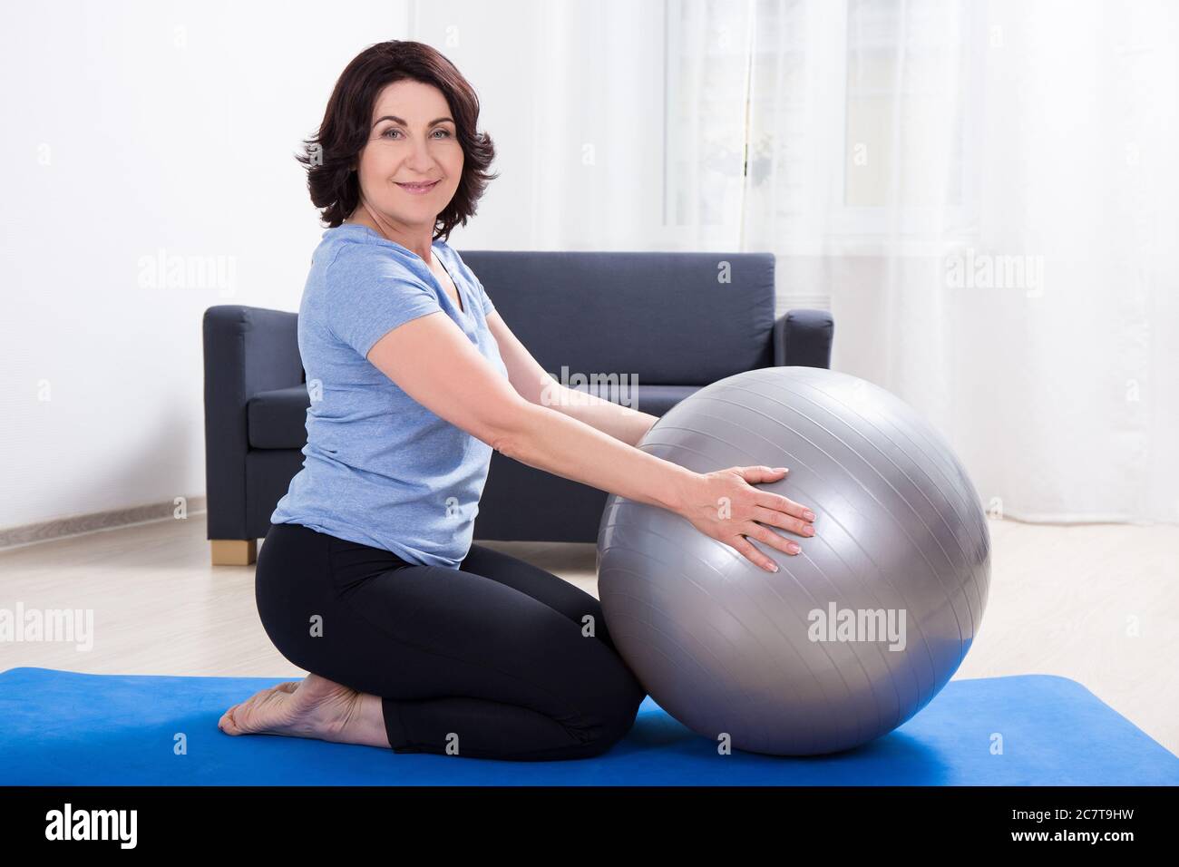 happy slim sporty mature woman doing exercises with fitness ball on ...