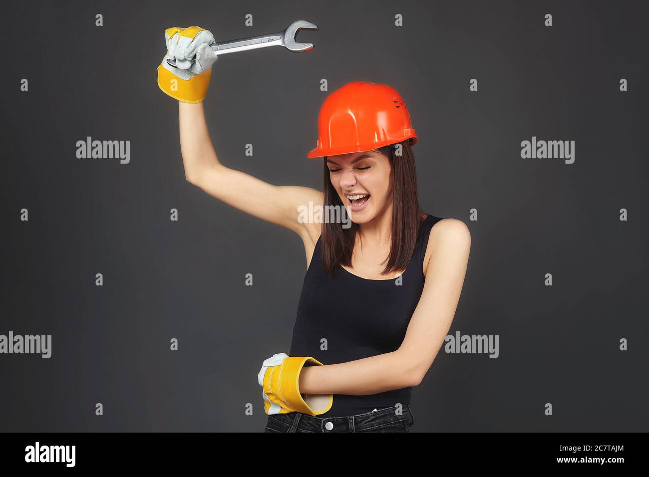 beautiful women in an orange helmet. holding a spanner in his hand ...