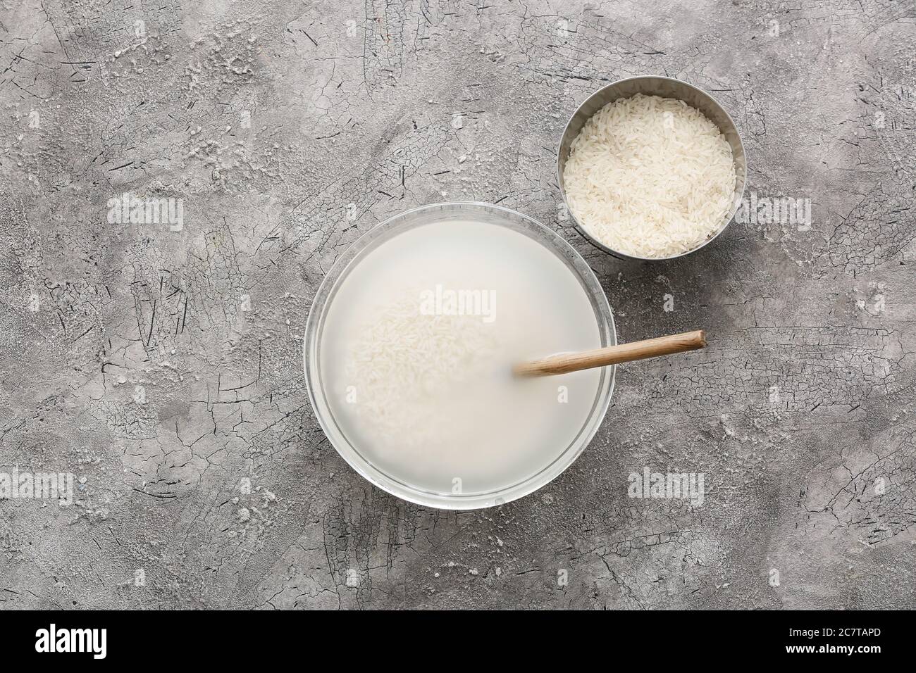 Bowls with rice and water on grey background Stock Photo - Alamy