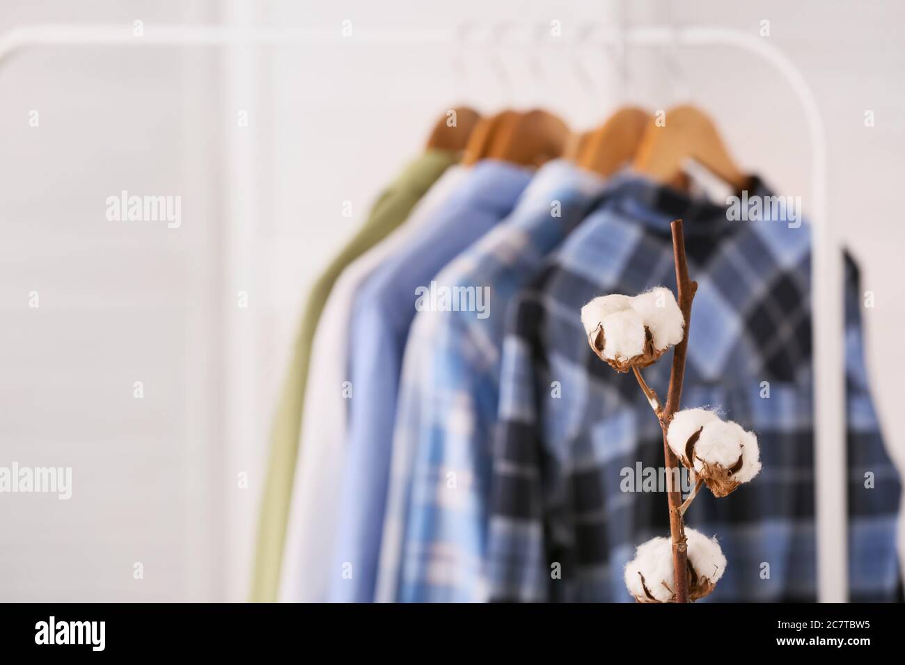 Cotton flowers and clothes hanging on rack in dressing room Stock Photo ...