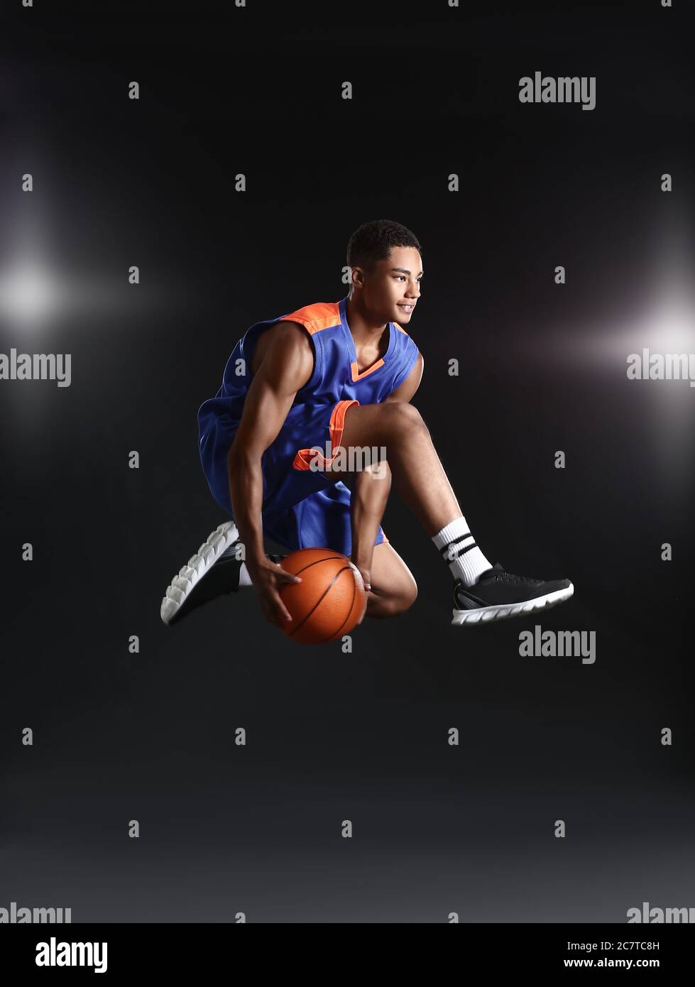 Young jumping African-American basketball player on dark background ...