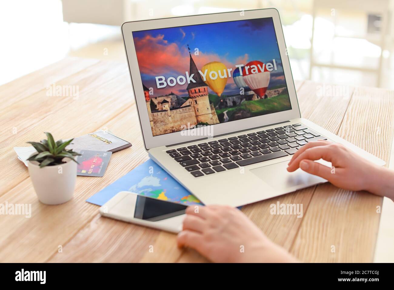 Woman with laptop booking tickets online at table Stock Photo - Alamy