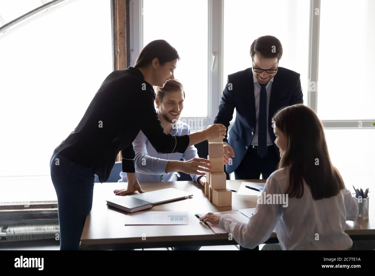 Excited diverse colleagues engaged in teambuilding activity at meeting ...
