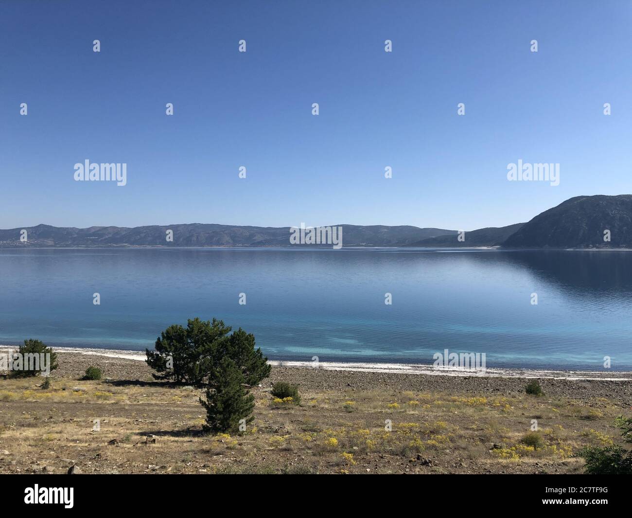 Aerial shot of a reflective lake on some mountains and blue sky ...
