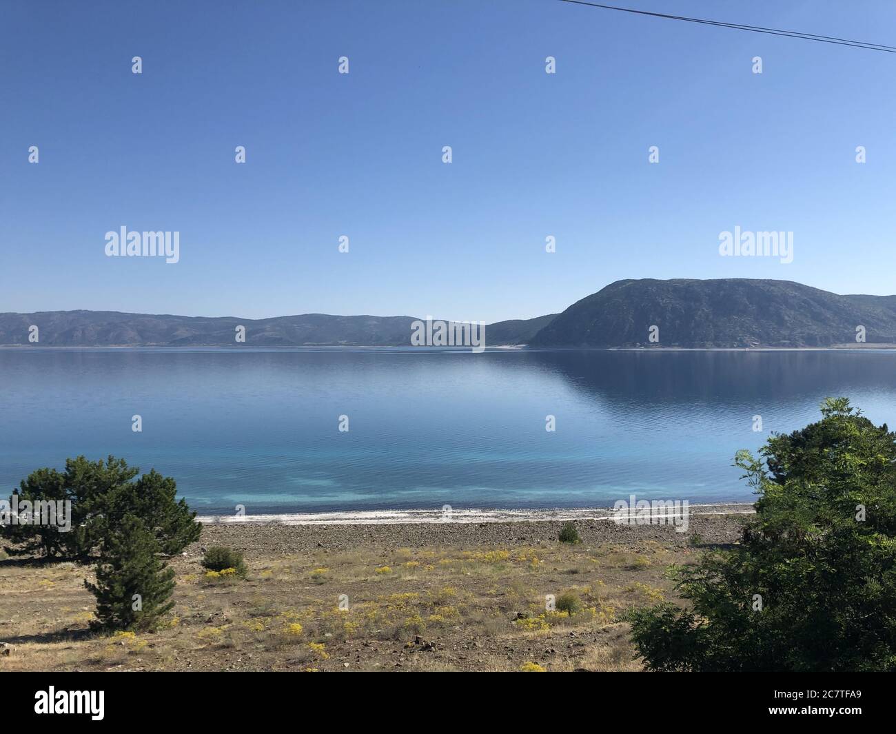 Aerial shot of a reflective lake on some mountains and blue sky ...