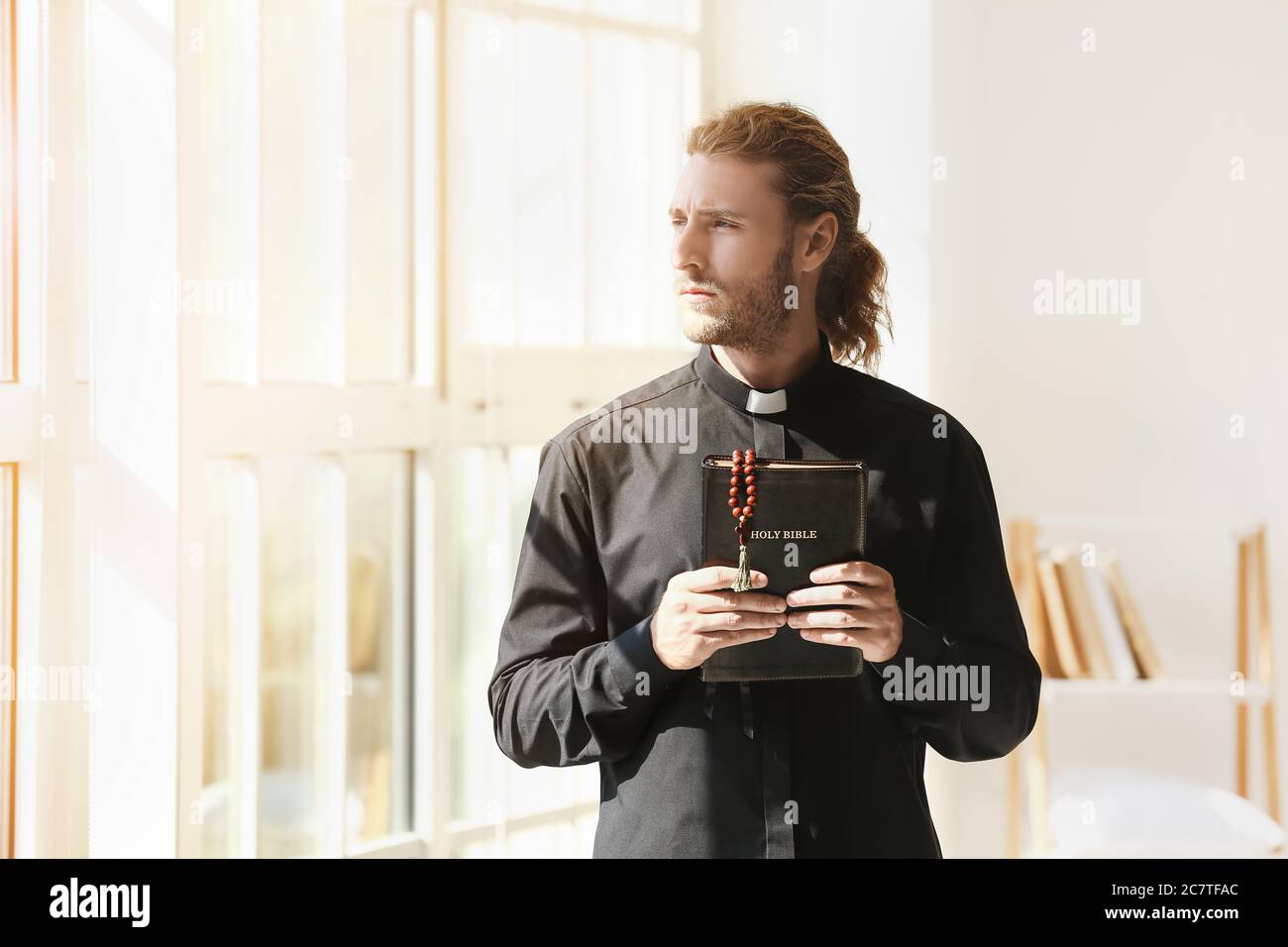 Male priest with Bible at home Stock Photo - Alamy