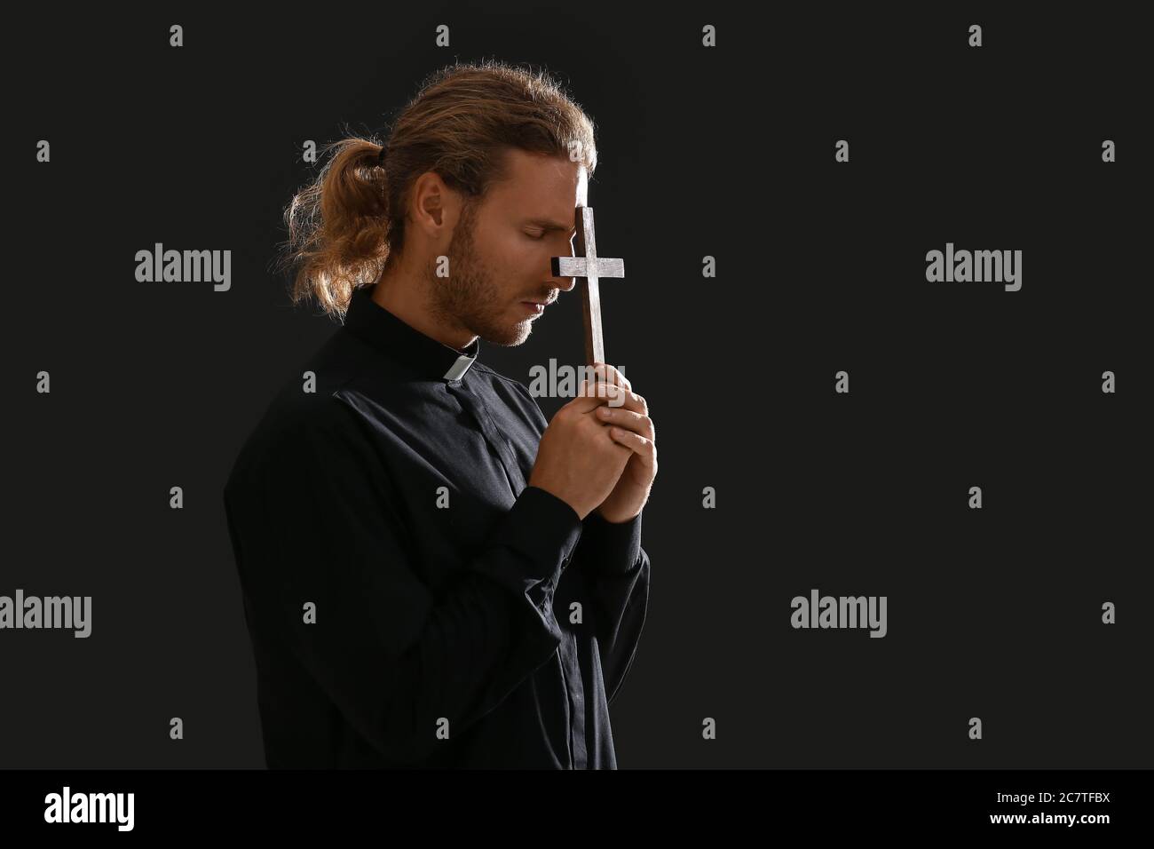 Handsome priest with cross on dark background Stock Photo - Alamy