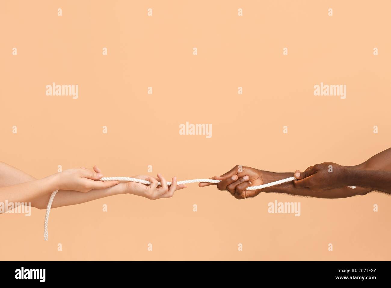 Caucasian woman and African-American man pulling rope on color ...