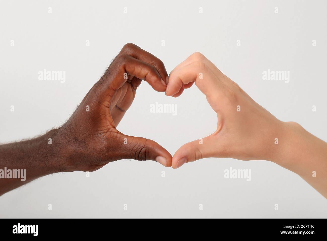 Caucasian woman and African-American man making heart with their hands ...
