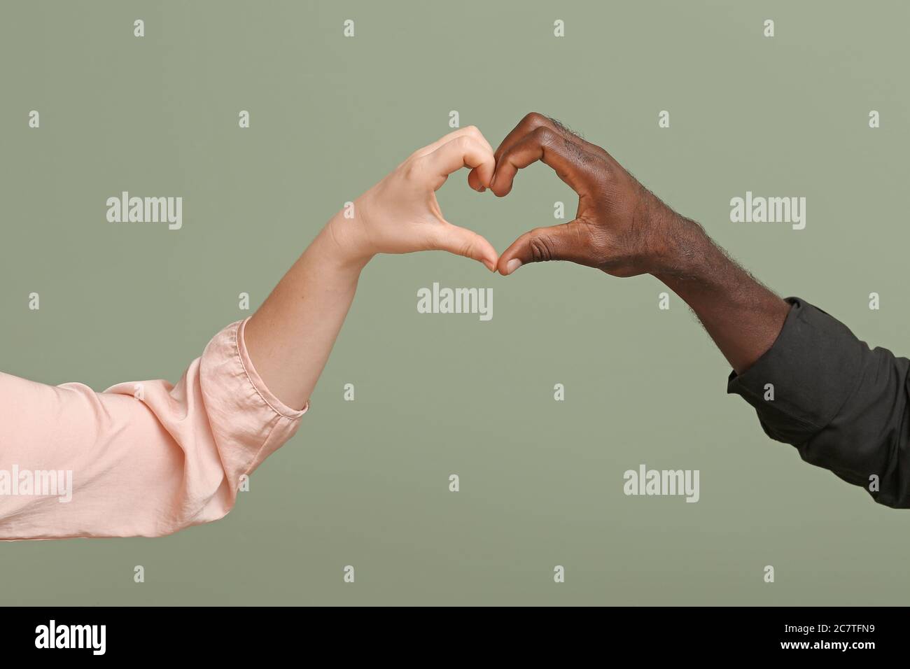 Caucasian woman and African-American man making heart with their hands ...