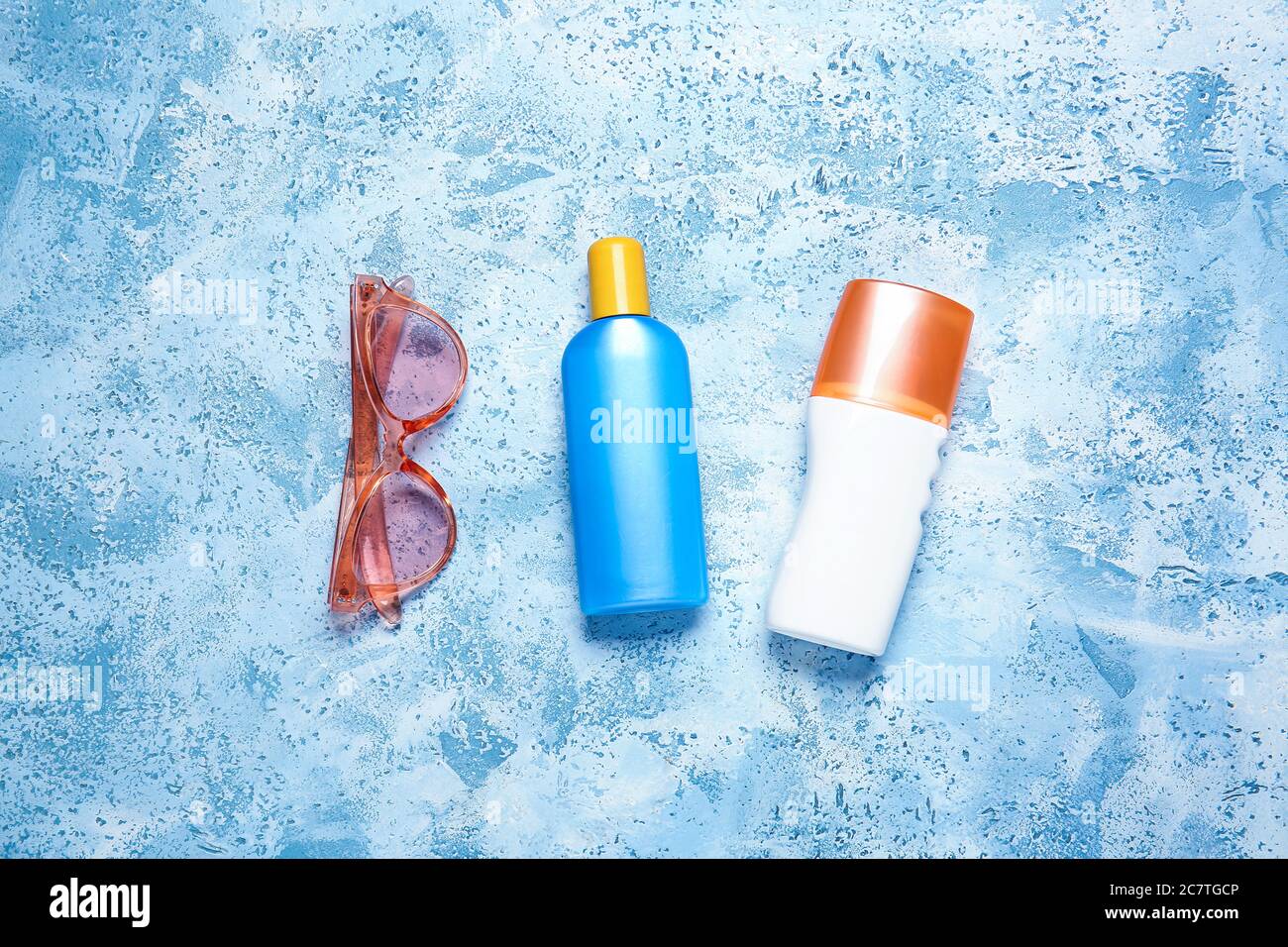 Bottles of sunscreen with sunglasses on color background Stock Photo ...