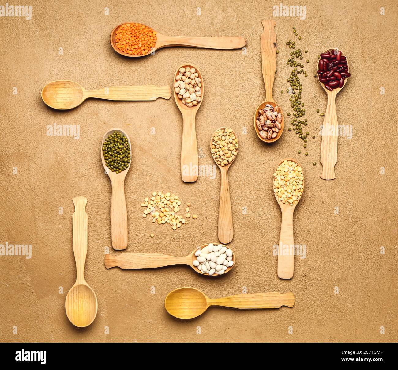 Spoons with raw legumes on color background Stock Photo - Alamy