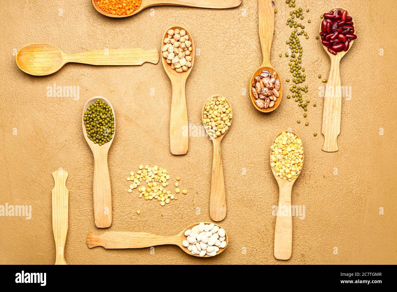 Spoons with raw legumes on color background Stock Photo - Alamy