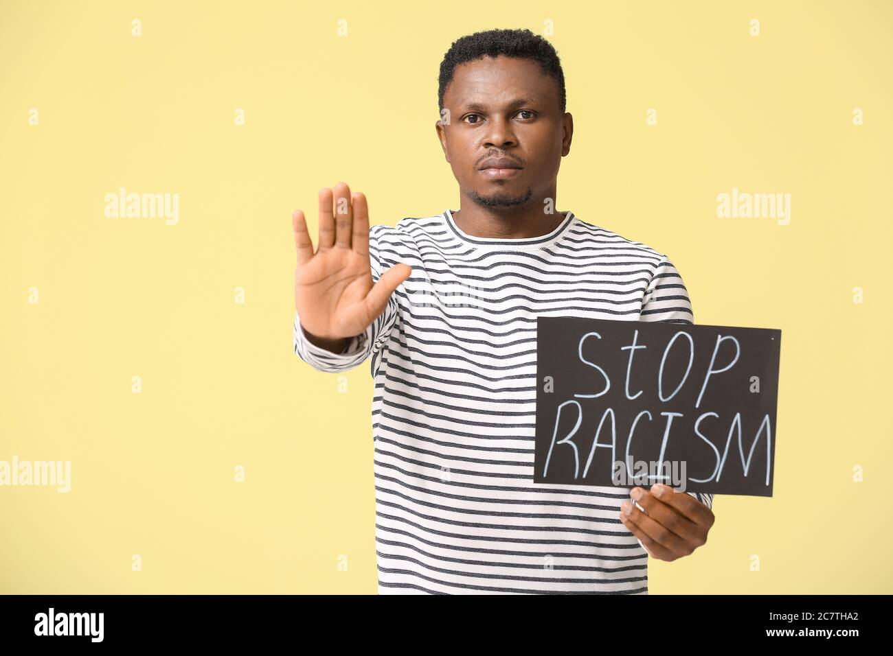 Sad African-American man with poster showing stop gesture on color ...