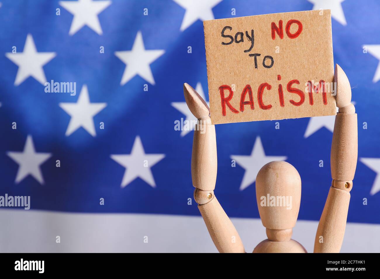 Mannequin with text SAY NO TO RACISM on poster near flag of USA Stock ...