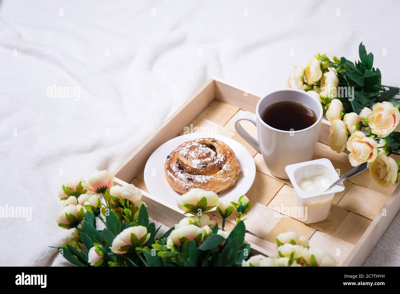 morning concept - breakfast with sweet bun, tea and yoghurt on wooden ...