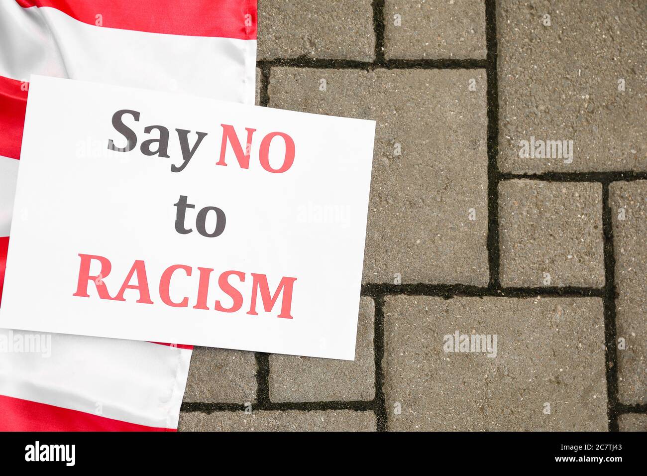 Paper with text SAY NO TO RACISM and flag of USA outdoors Stock Photo ...