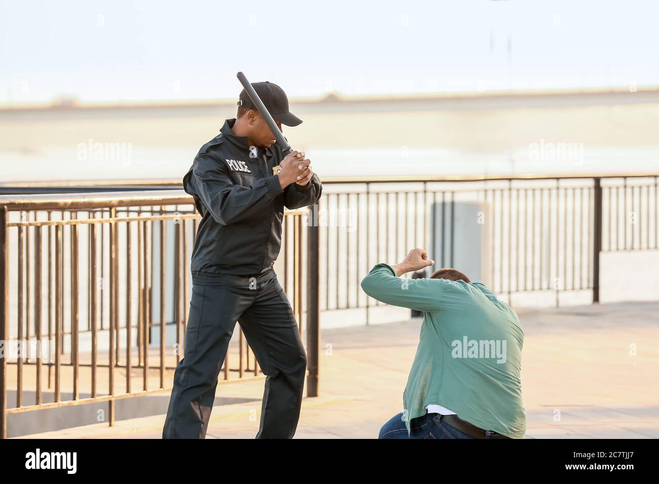 Aggressive African-American police officer mistreating man outdoors ...