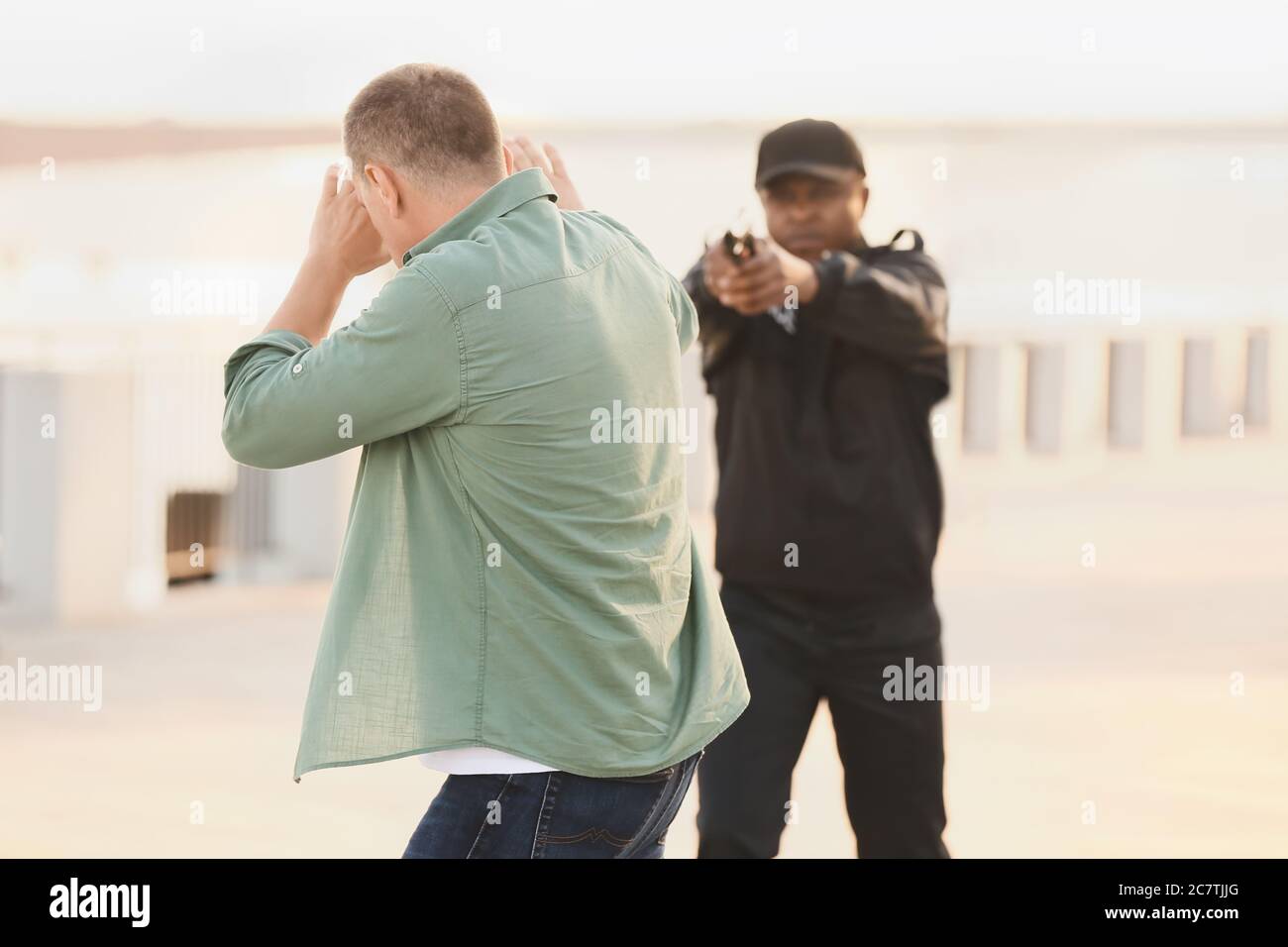 Aggressive African-American police officer mistreating man outdoors ...