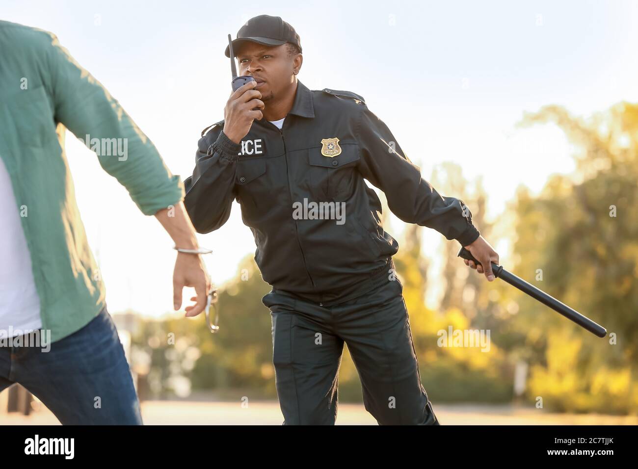 Aggressive African-American police officer mistreating man outdoors ...
