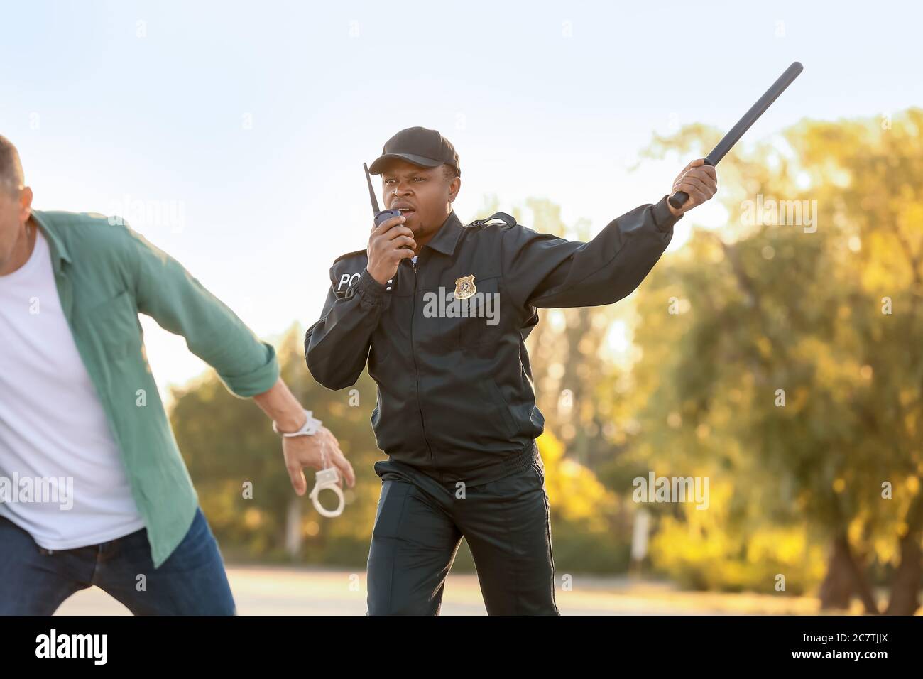 Aggressive African-American police officer mistreating man outdoors ...