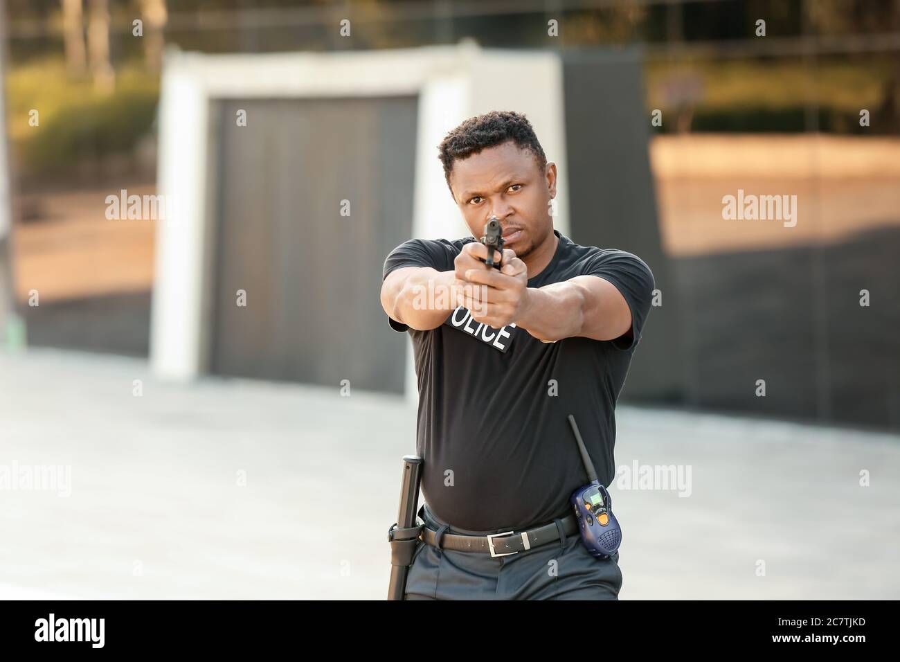 Aggressive African-American police officer with gun outdoors Stock ...