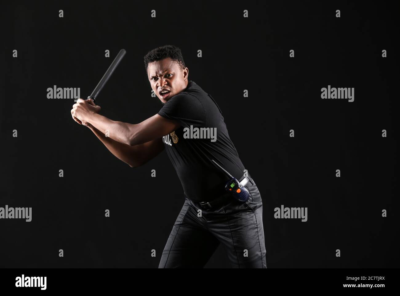 Aggressive African-American police officer with baton on dark ...
