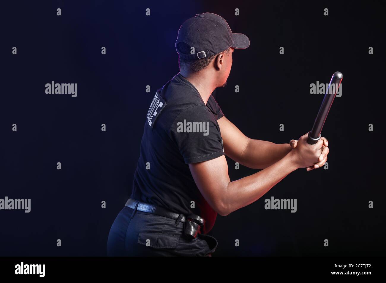 Aggressive African-American police officer with baton on dark ...