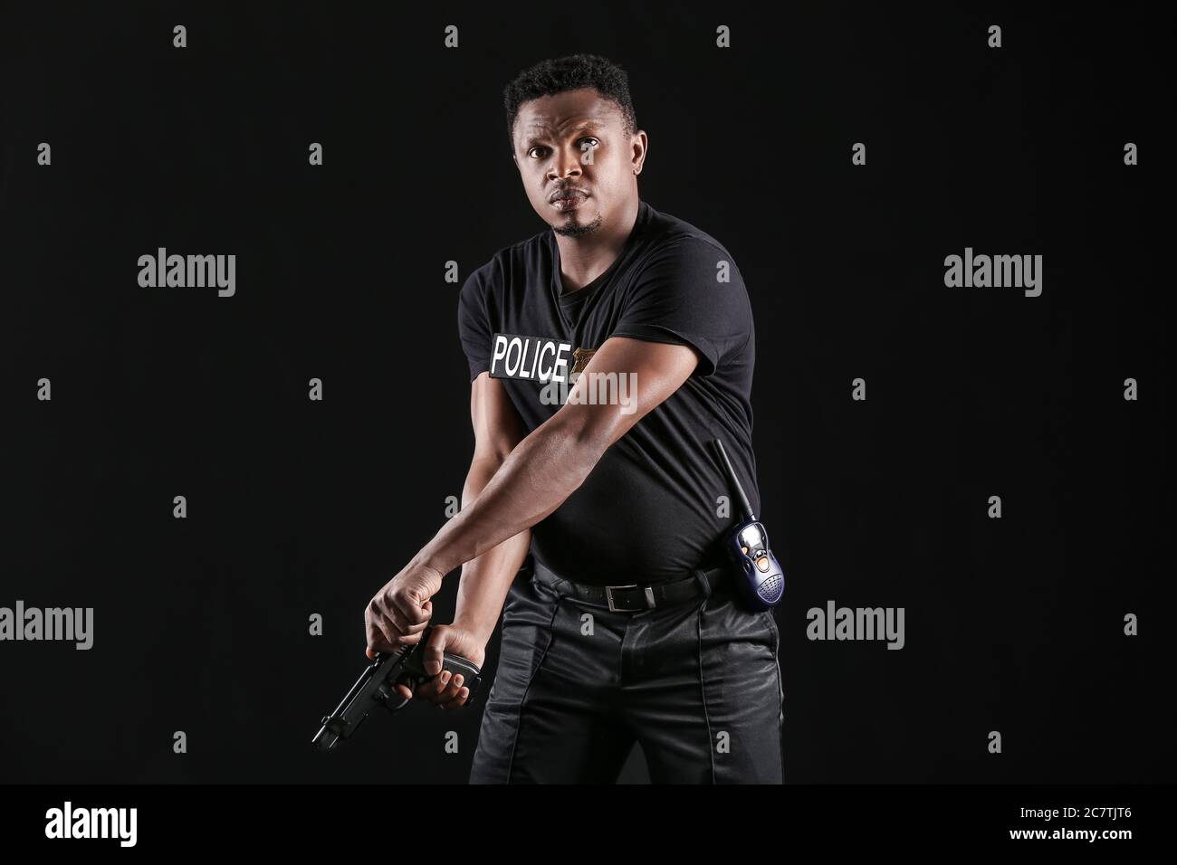 Aggressive African-American police officer with gun on dark background ...