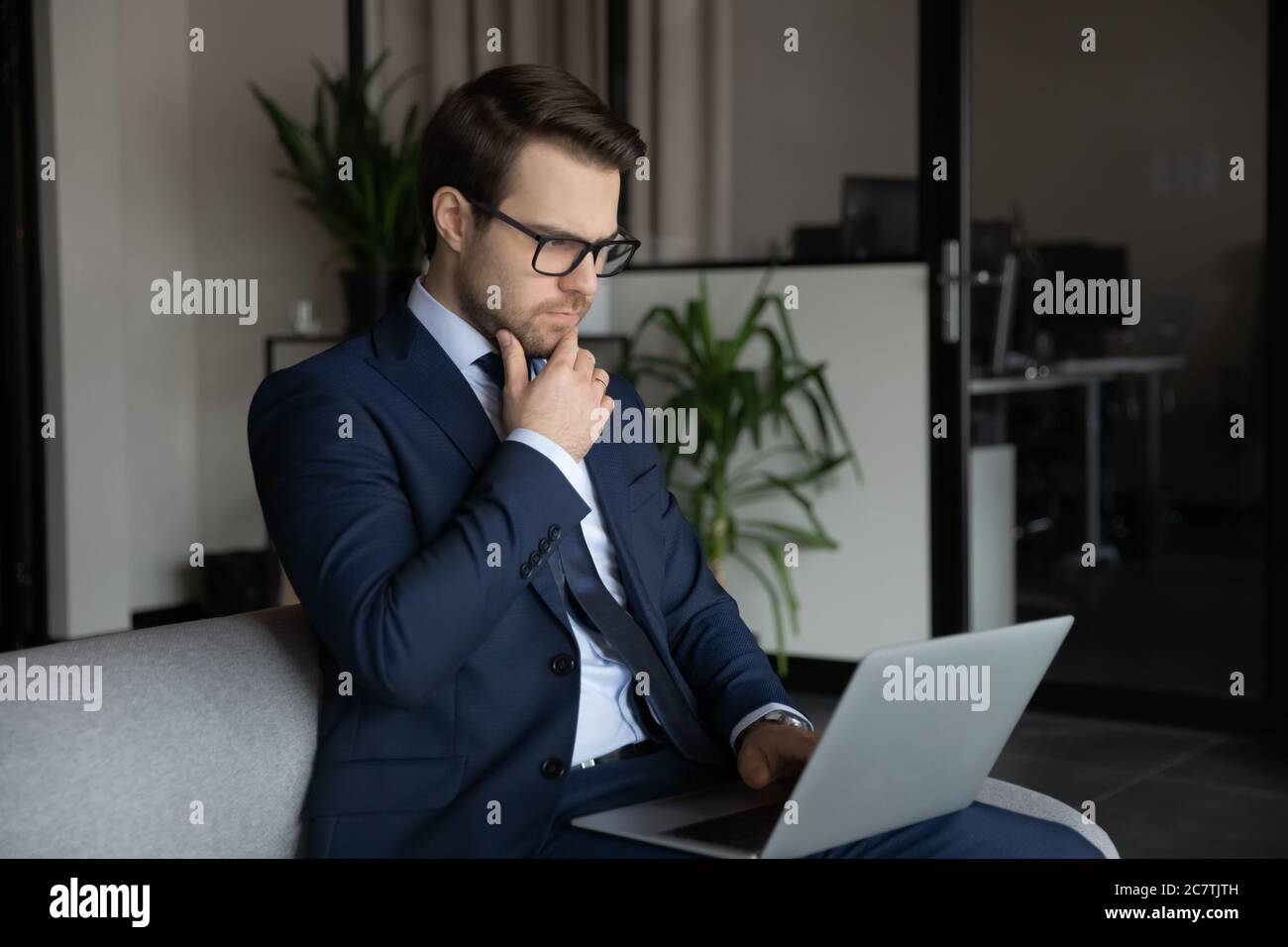 Serious Caucasian businessman look at laptop screen thinking Stock ...