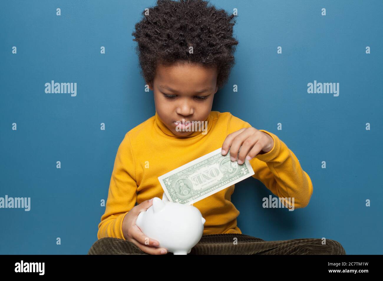 African American boy holding one us dollar and money box on blue ...