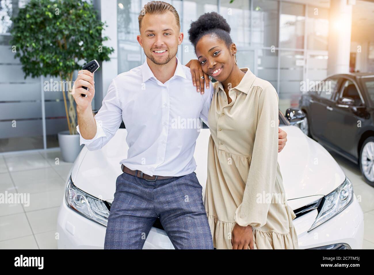 young married couple with keys from their new auto. diverse man and ...