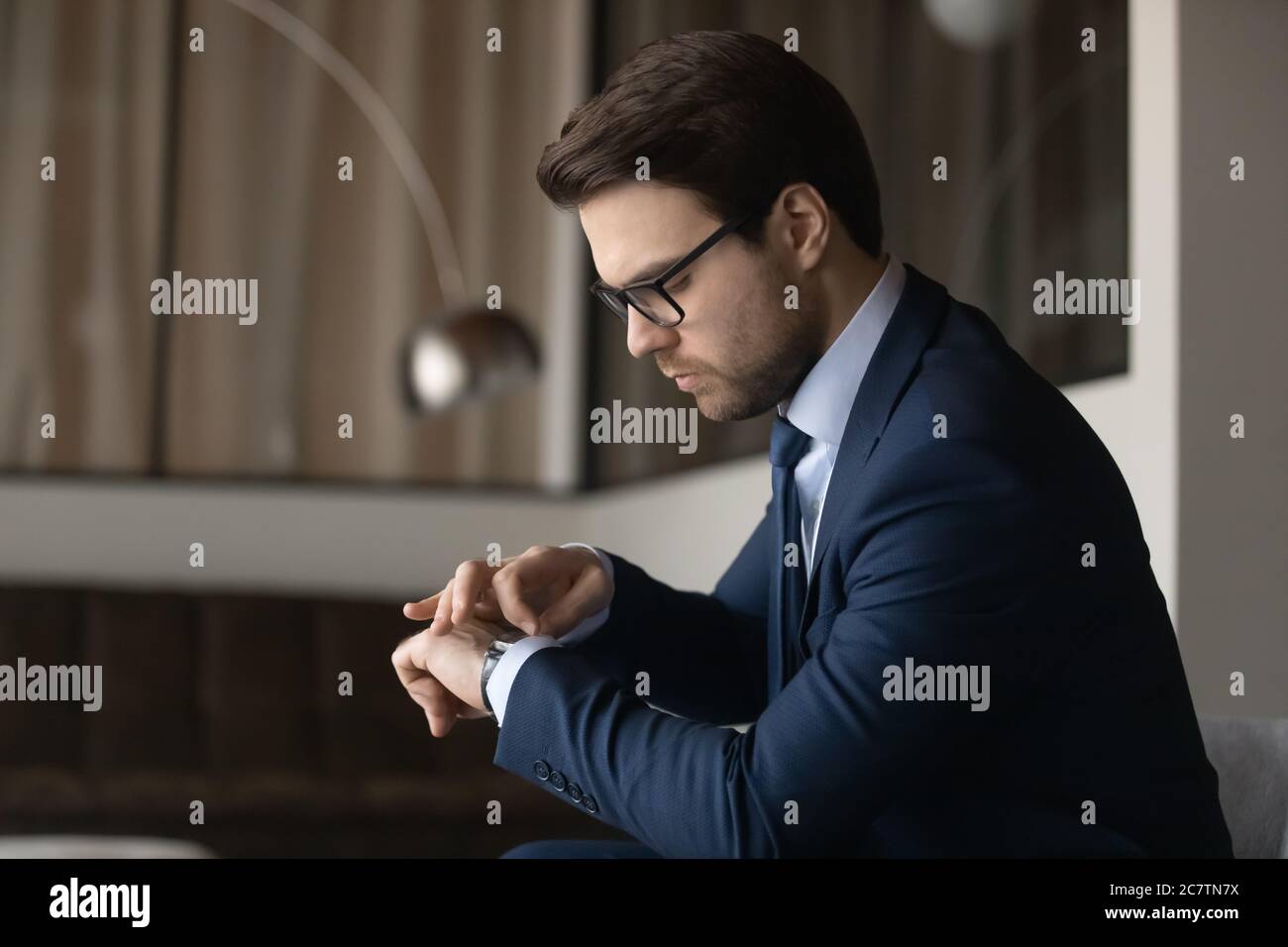 Serious businessman look at hand watch checking time Stock Photo - Alamy