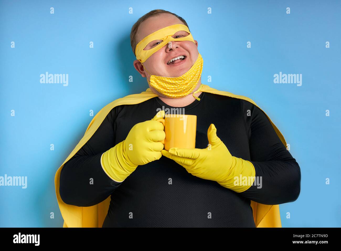 happy fat superhero drinks a cup of tea isolated over blue background ...