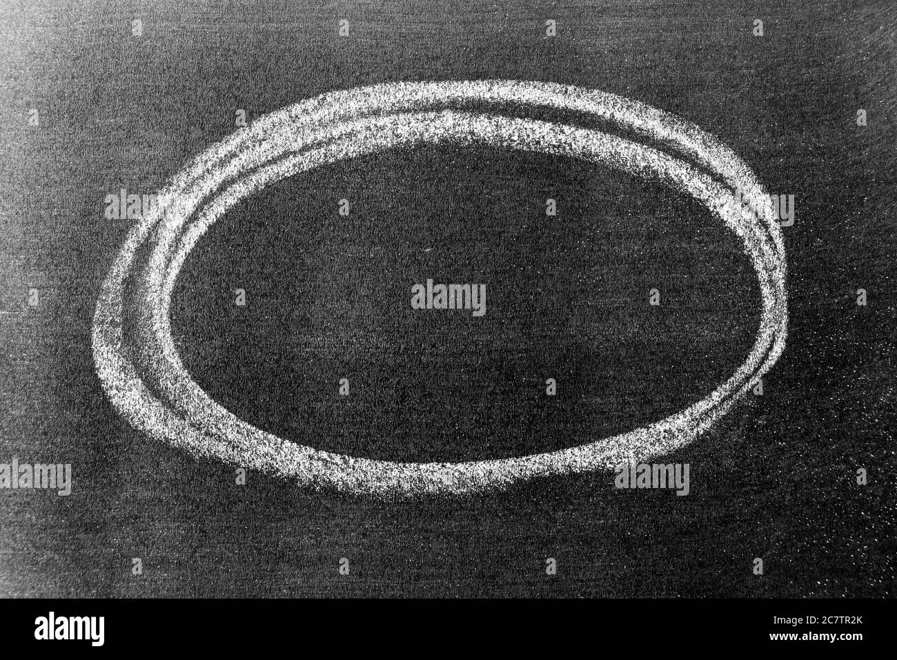 White color chalk hand drawing in circle or oval shape on black board ...